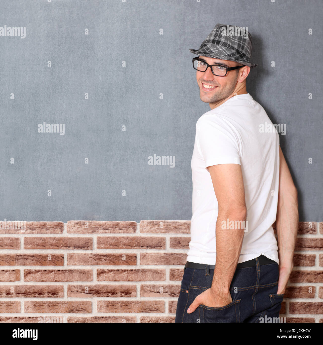 Trendy guy leaning on brick wall Stock Photo - Alamy