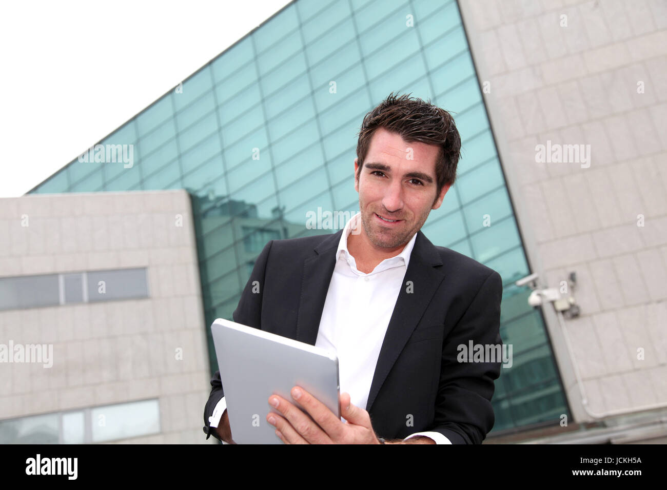 Man using electronic tablet in front of modern building Stock Photo - Alamy