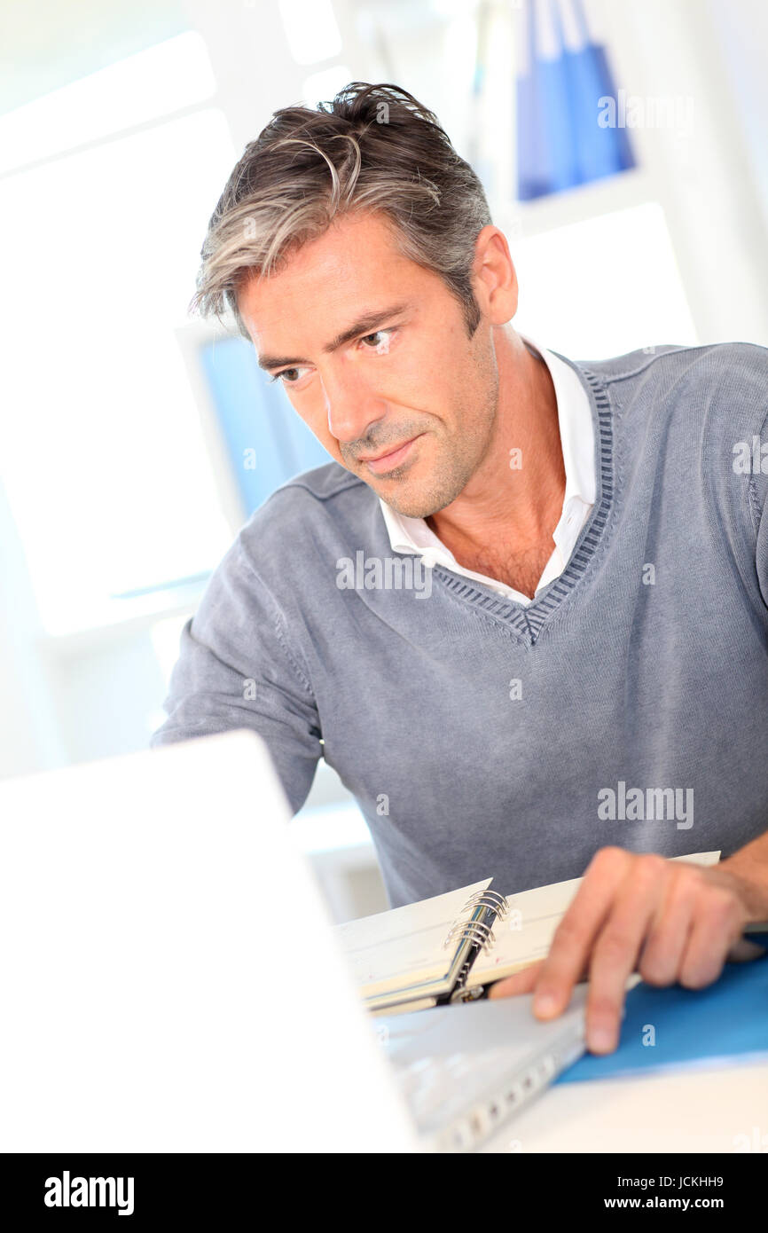 Man sitting in office in front of laptop computer Stock Photo - Alamy