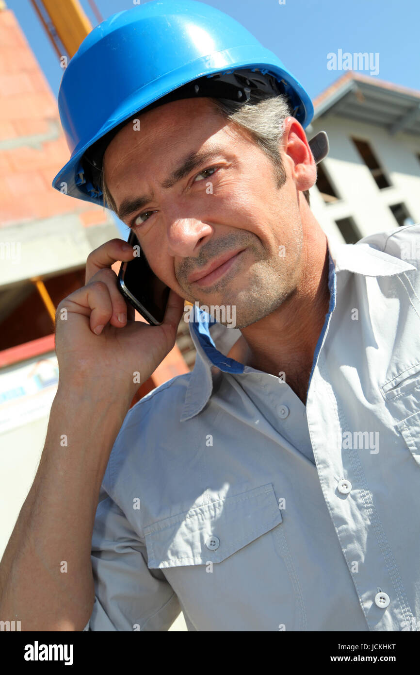 Engineer with blue security helmet talking on mobile phone Stock Photo ...