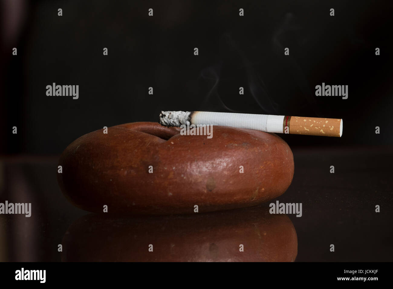 Cigratte burning on a ashtray Stock Photo - Alamy
