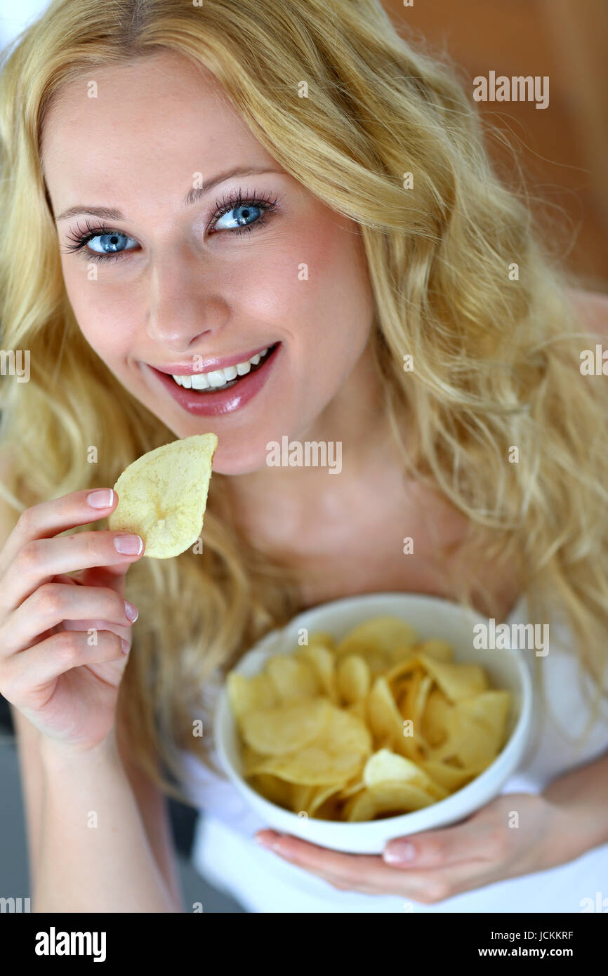 Smiling woman eating potato chips Stock Photo - Alamy