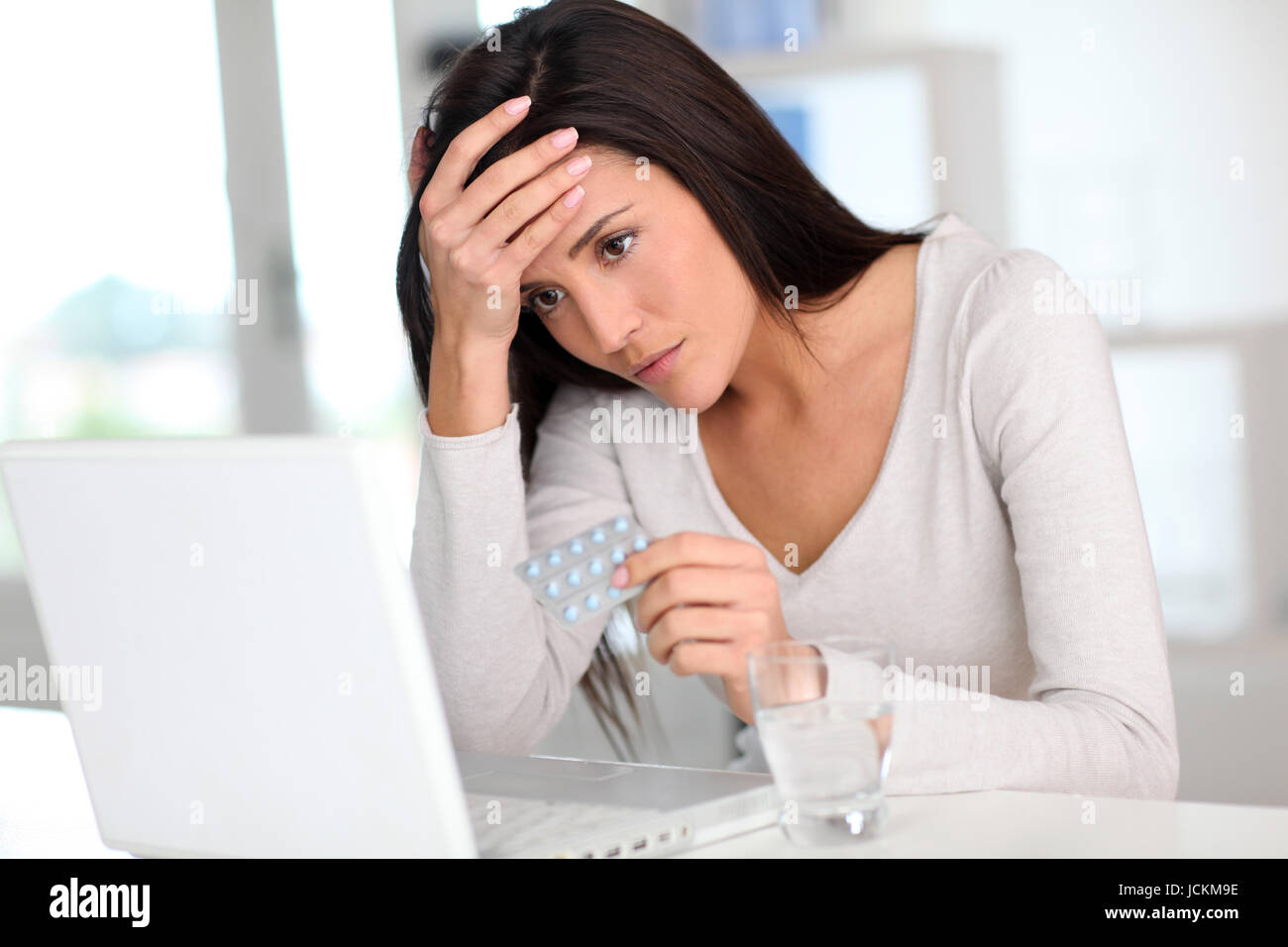 Woman with headache in front of laptop computer Stock Photo - Alamy