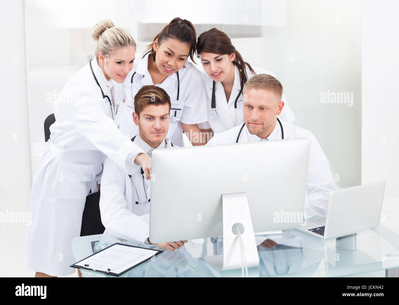 Team of doctors using desktop PC together at desk in clinic Stock Photo ...