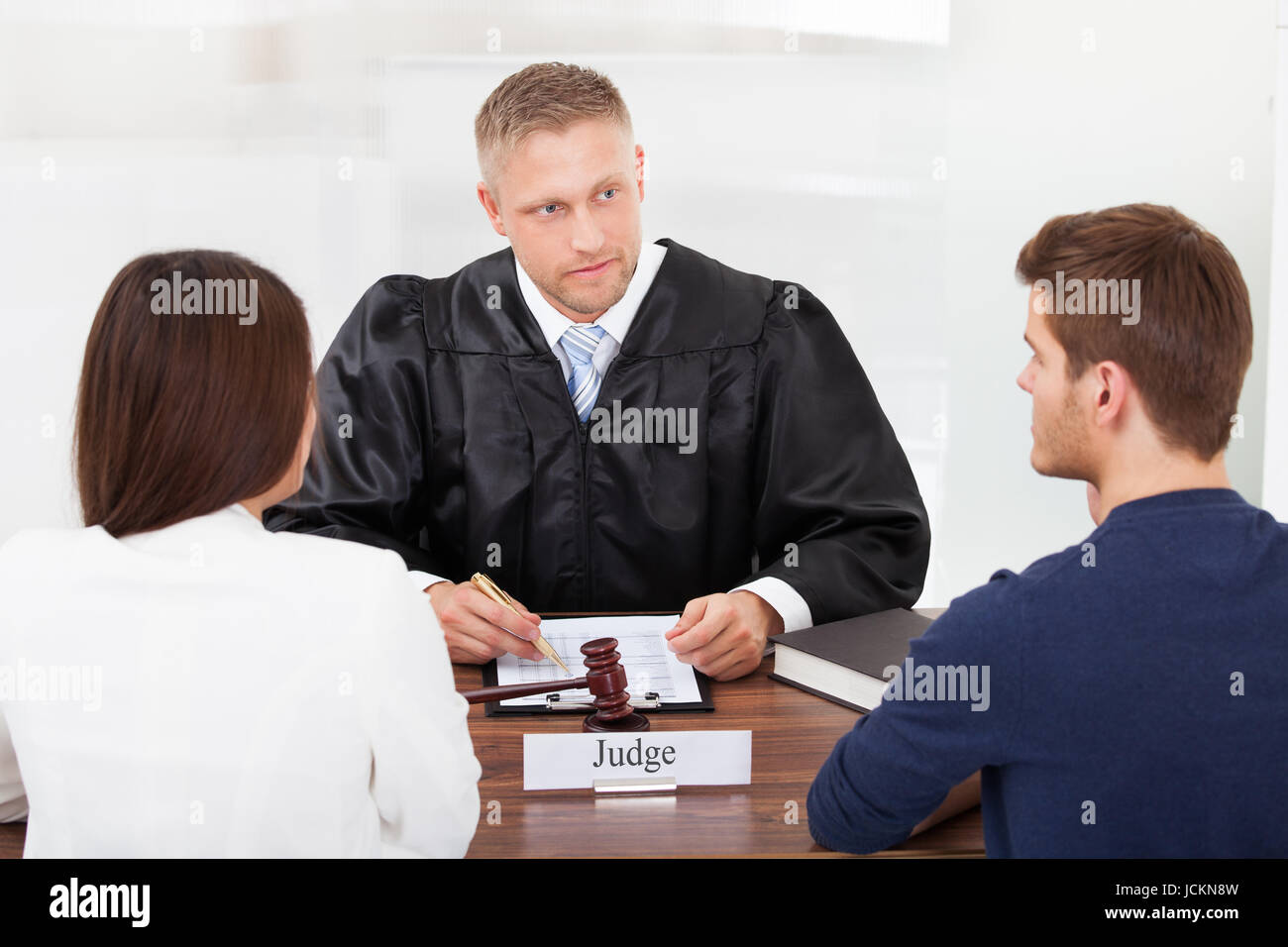 Rear view of couple with judge writing at desk in court Stock Photo - Alamy