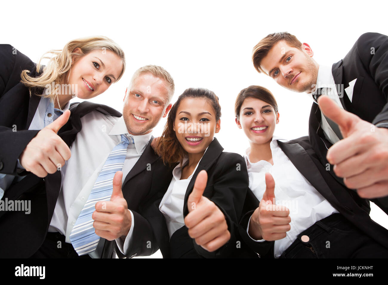 Low angle portrait of business people gesturing thumbs up against white ...