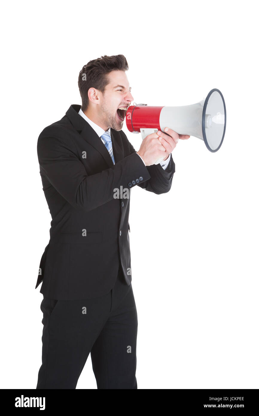 Full length of young businessman screaming into megaphone over white ...