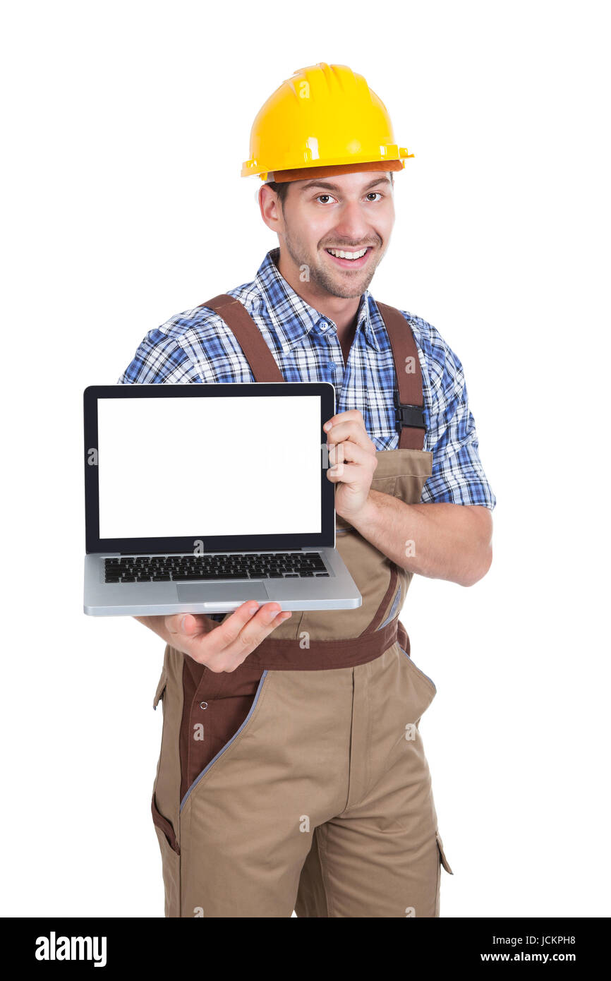 Portrait of young manual worker displaying laptop over white background ...