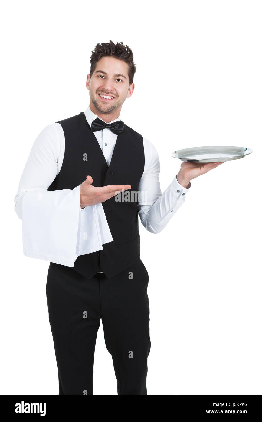 Portrait of confident young waiter with napkin and serving tray ...