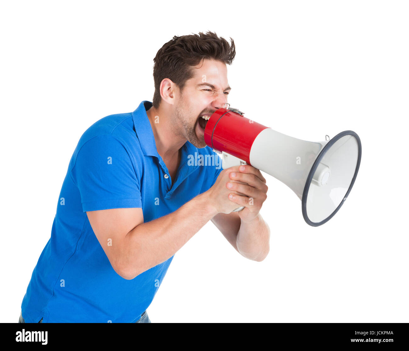 Full length of aggressive young man screaming into bullhorn while ...