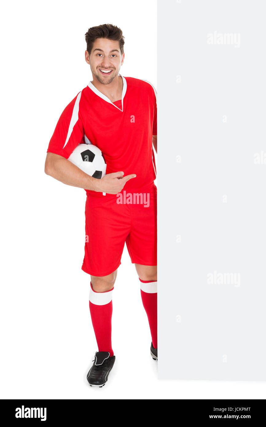 Full length portrait of young soccer player with football pointing at ...