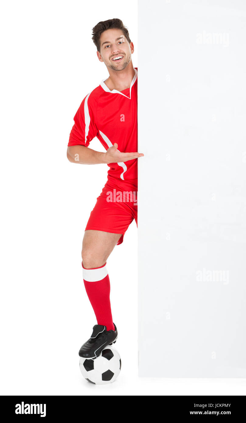 Full length portrait of young soccer player with football pointing at ...