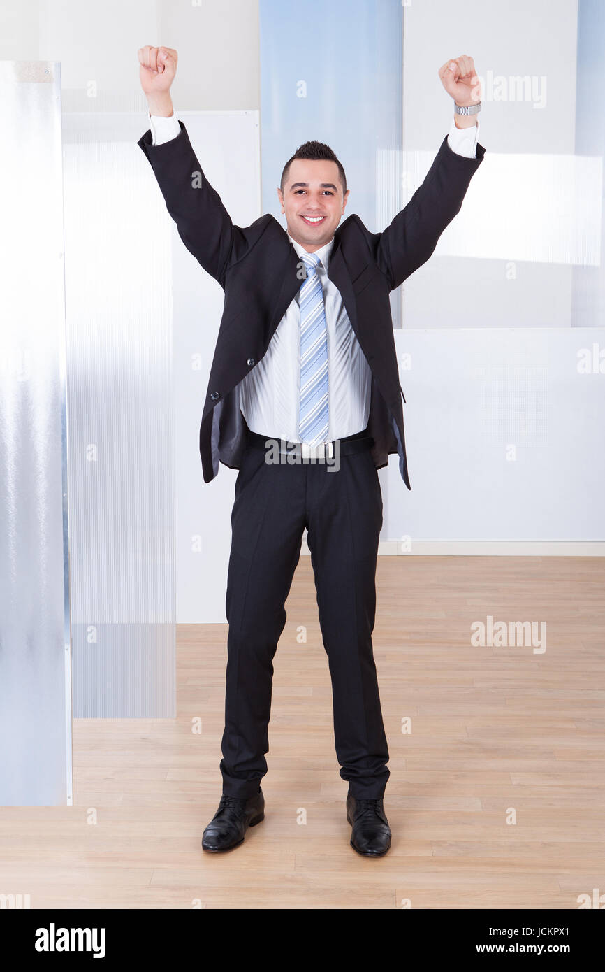 Full length portrait of successful businessman standing arms raised in ...
