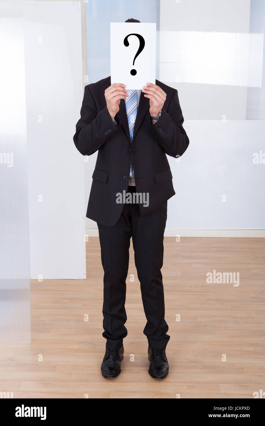 Full length of young businessman holding paper with question mark in ...