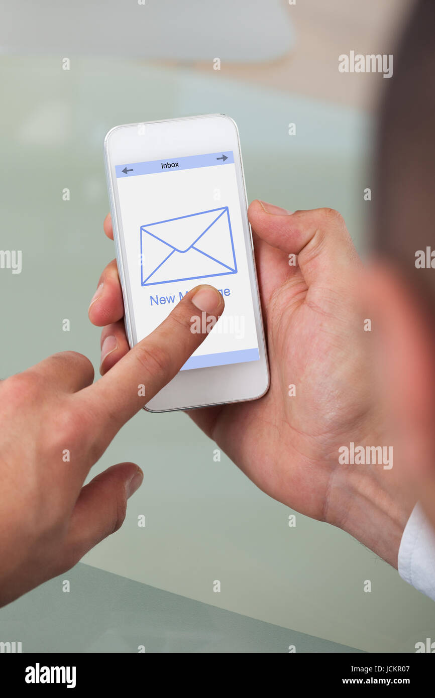 Cropped image of businessman opening message on smart phone in office ...