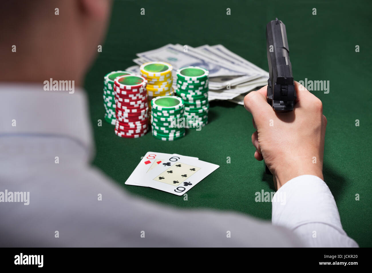 Rear view of man playing poker while pointing gun in casino Stock Photo ...
