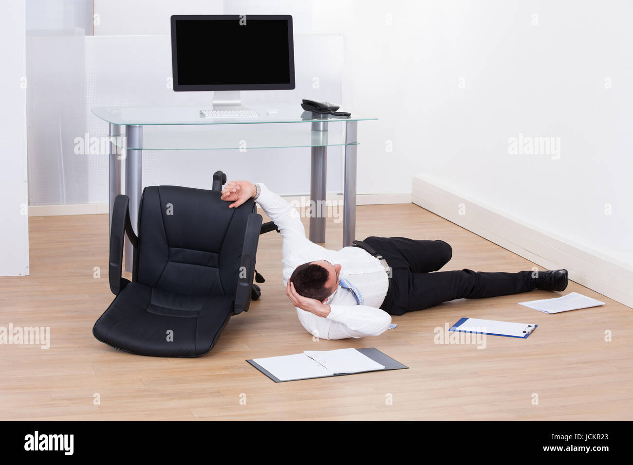 Full length of young businessman fallen from office chair Stock Photo ...