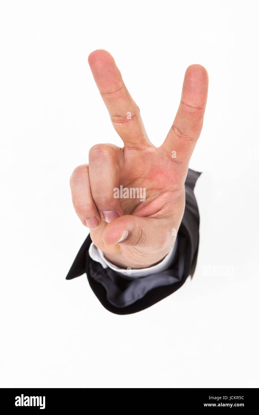 Businessman's hand breaking through white paper wall gesturing victory ...