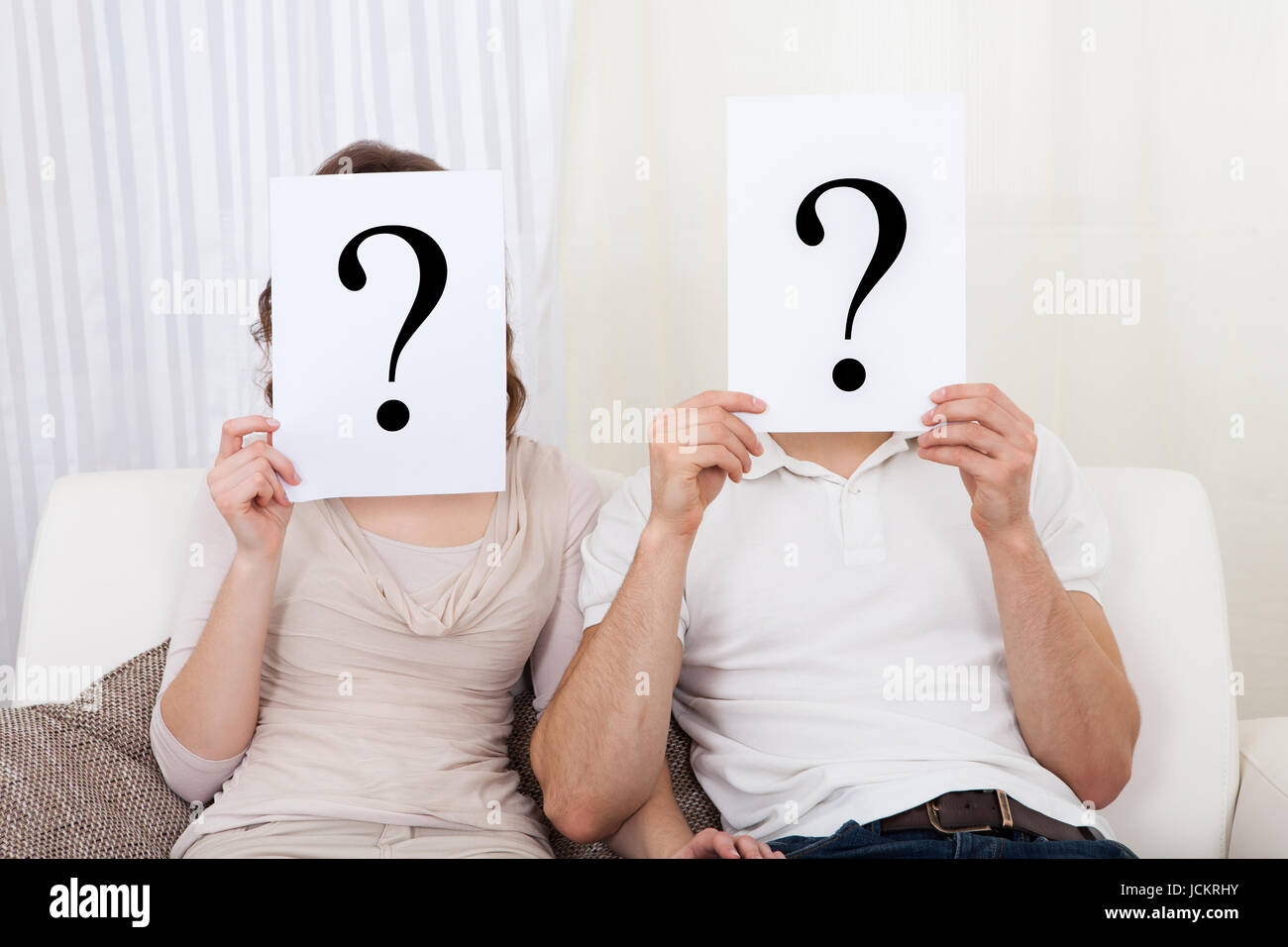 Couple in the living room with question marks in front of their faces ...
