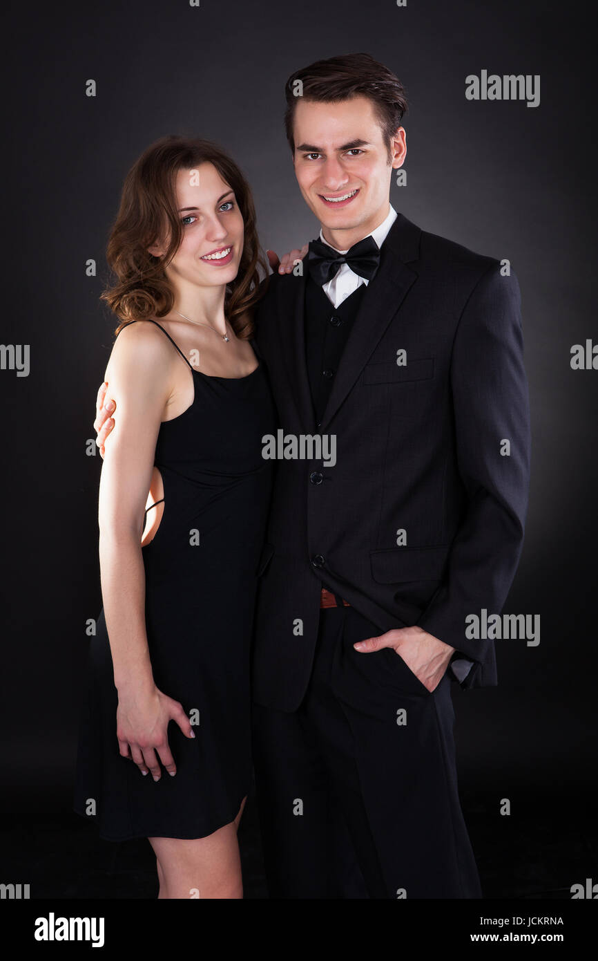 Portrait of an elegant couple standing together isolated over black ...