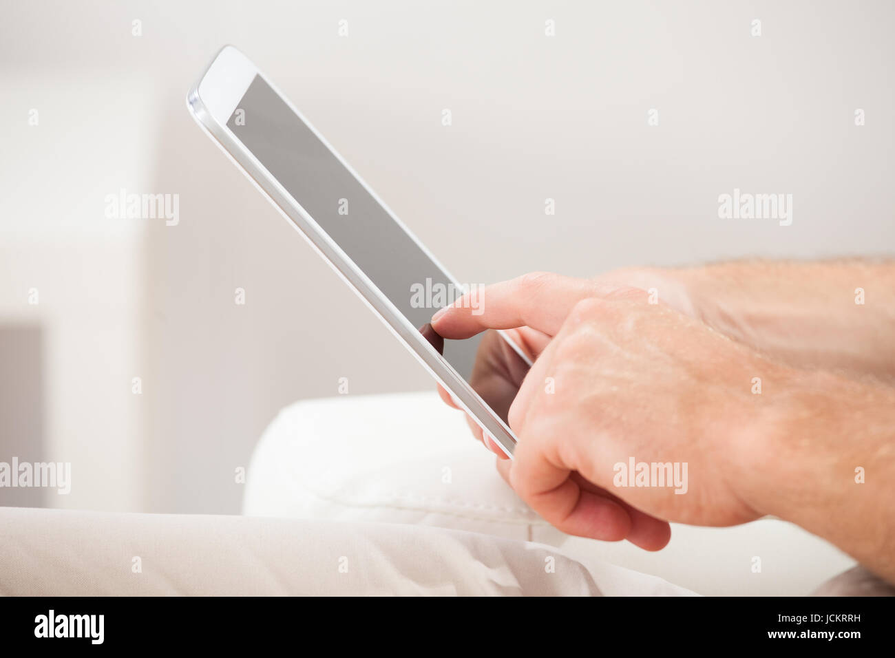 Cropped image of man touching smartphone on sofa at home Stock Photo ...