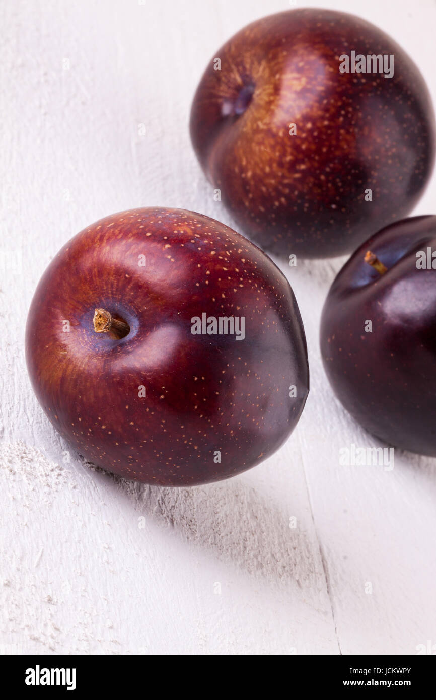 Frische glänzende saftige Pflaumen mit reifer Farbe mit Stiel nach oben ...
