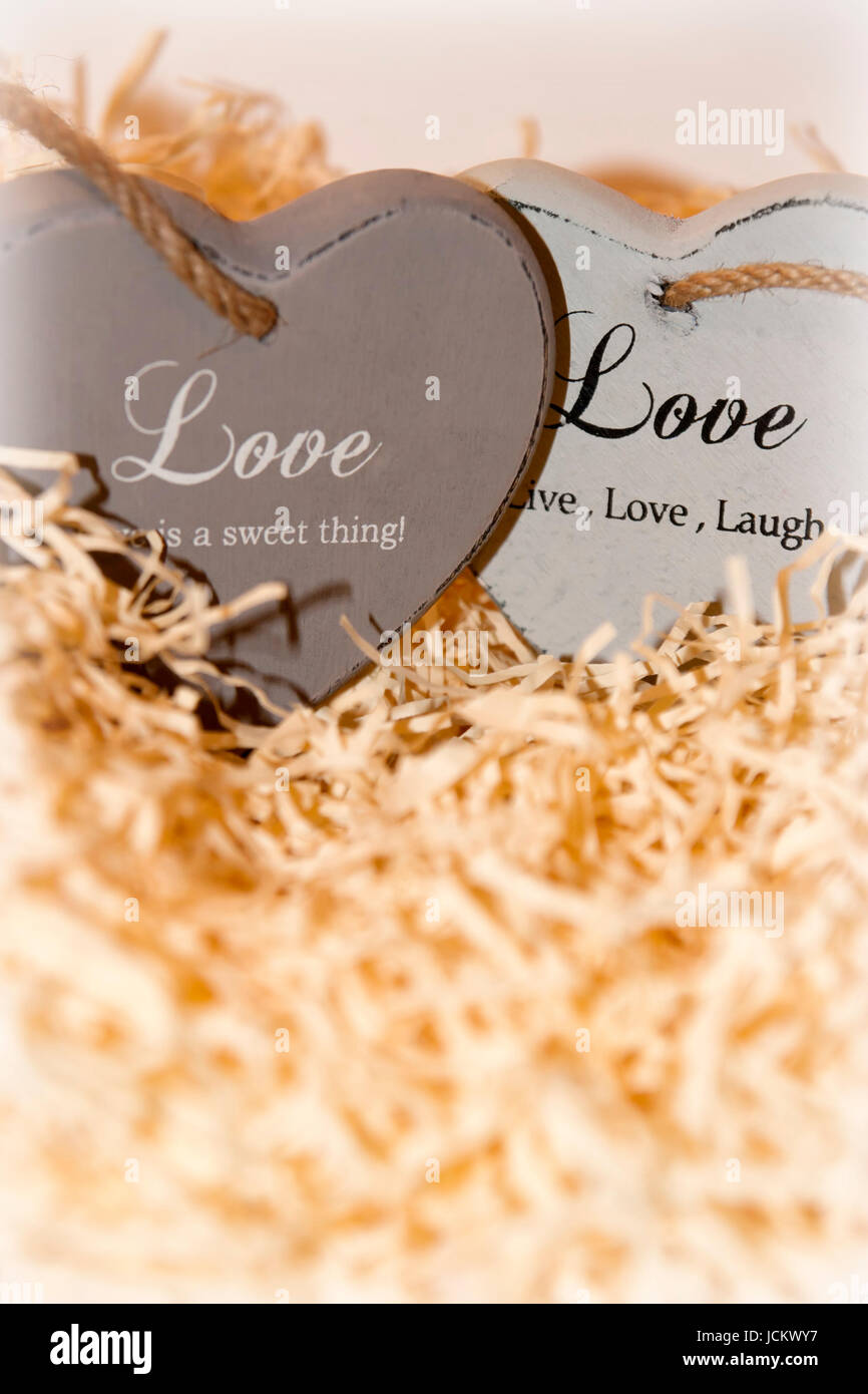 two grey wooden love hearts in a love nest made of straw with loving ...