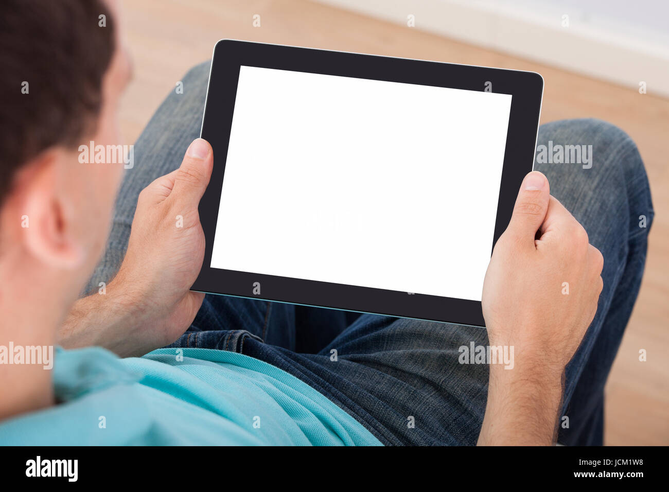 Closeup of mid adult man looking at blank screen of digital tablet at ...