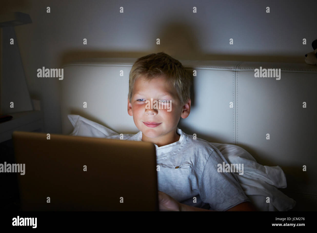 Boy Using Laptop In Bed At Night Stock Photo - Alamy