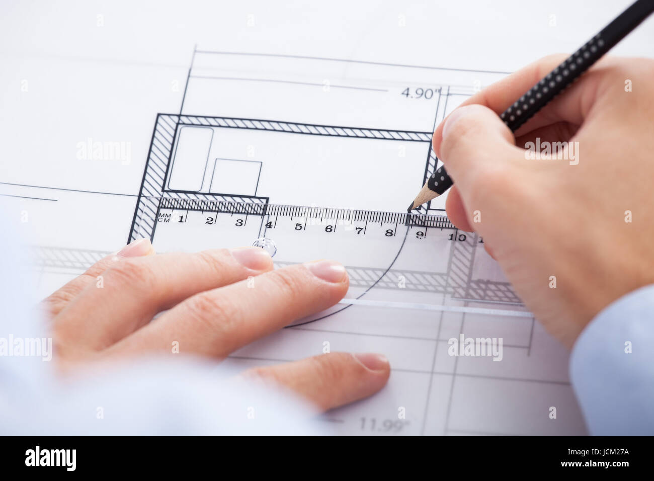 Closeup of architect's hands using pencil and ruler on blueprint in ...