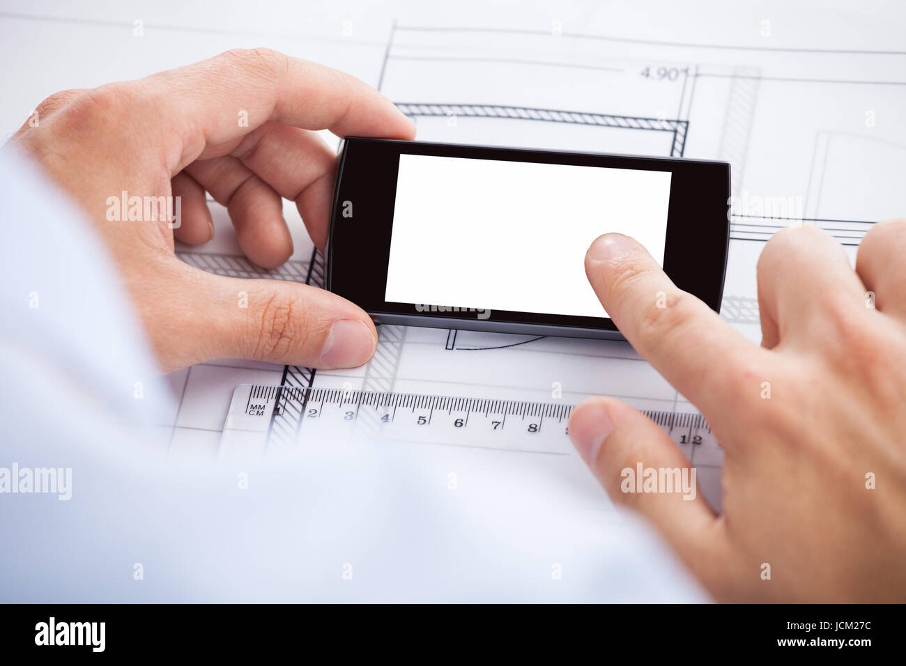 Closeup of architect touching smartphone's screen over blueprint in ...