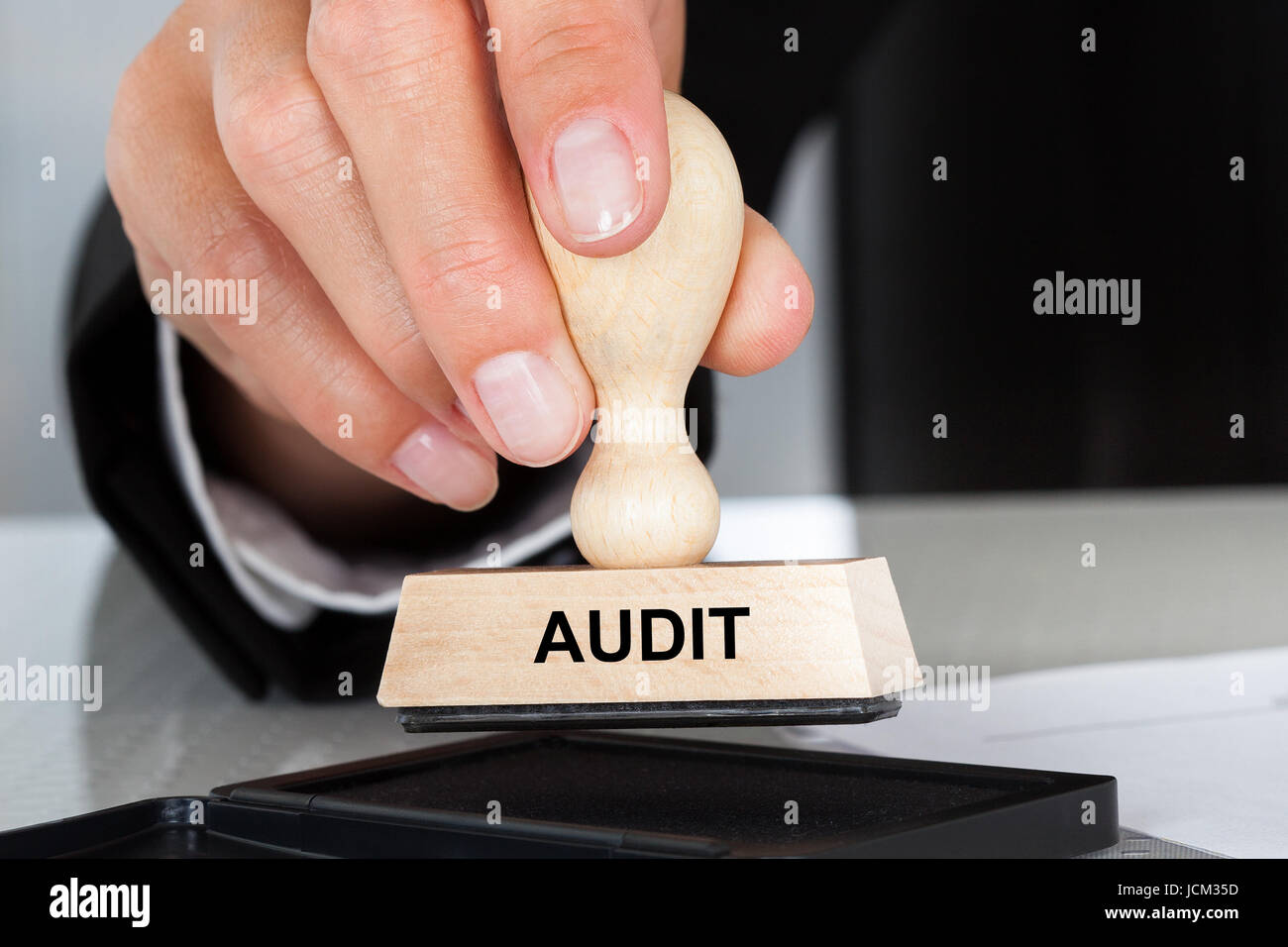 Closeup of hand holding rubber stamp with Audit sign at table in office ...