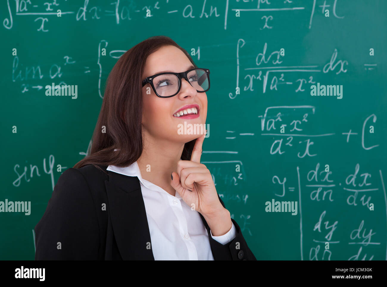 Thoughtful young teacher looking at chalkboard in classroom Stock Photo ...