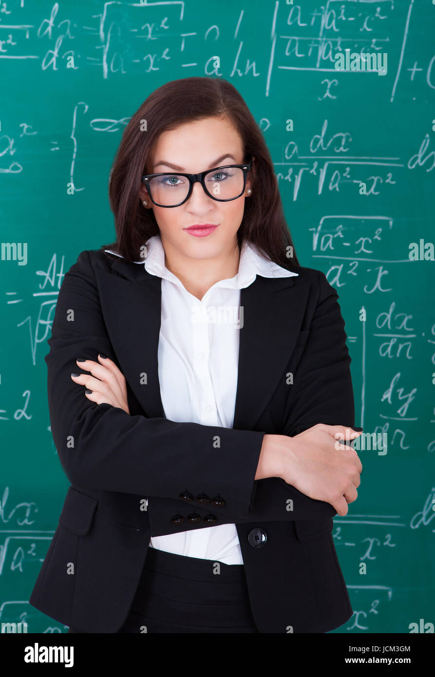 Portrait of confident young teacher standing arms crossed against ...