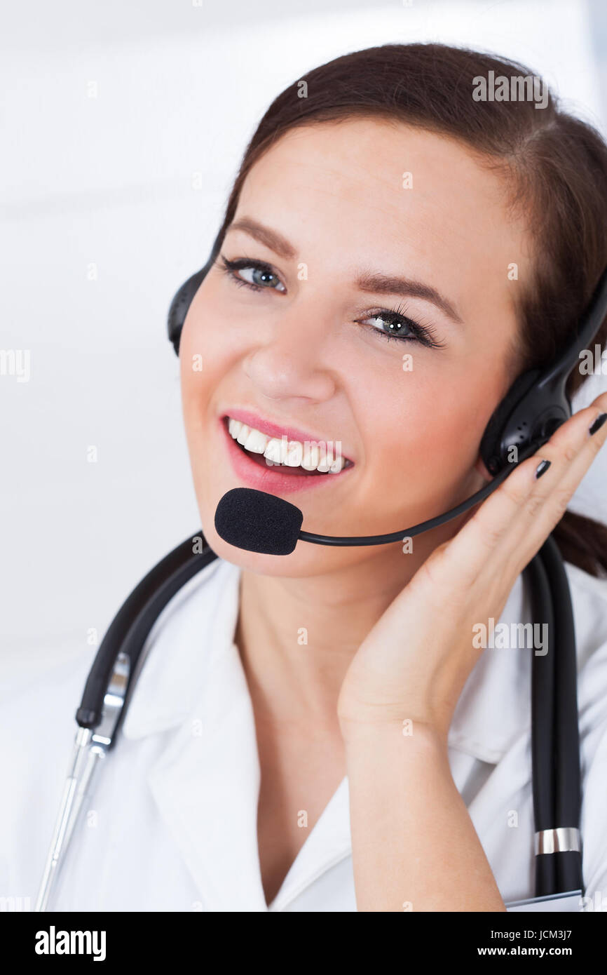 Portrait of confident young female doctor wearing headset in hospital ...