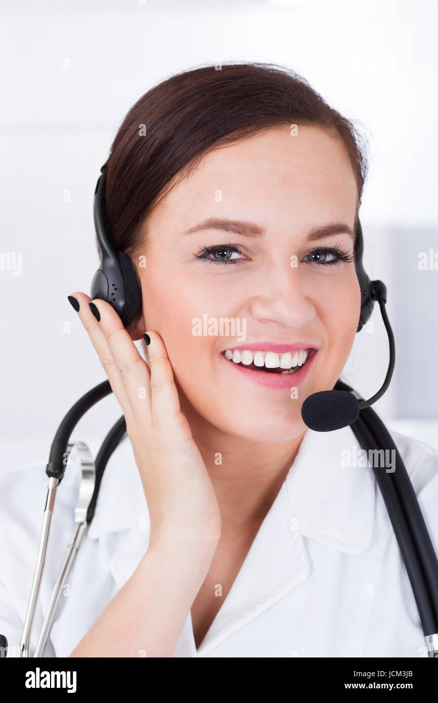 Portrait of confident young female doctor wearing headset in hospital ...