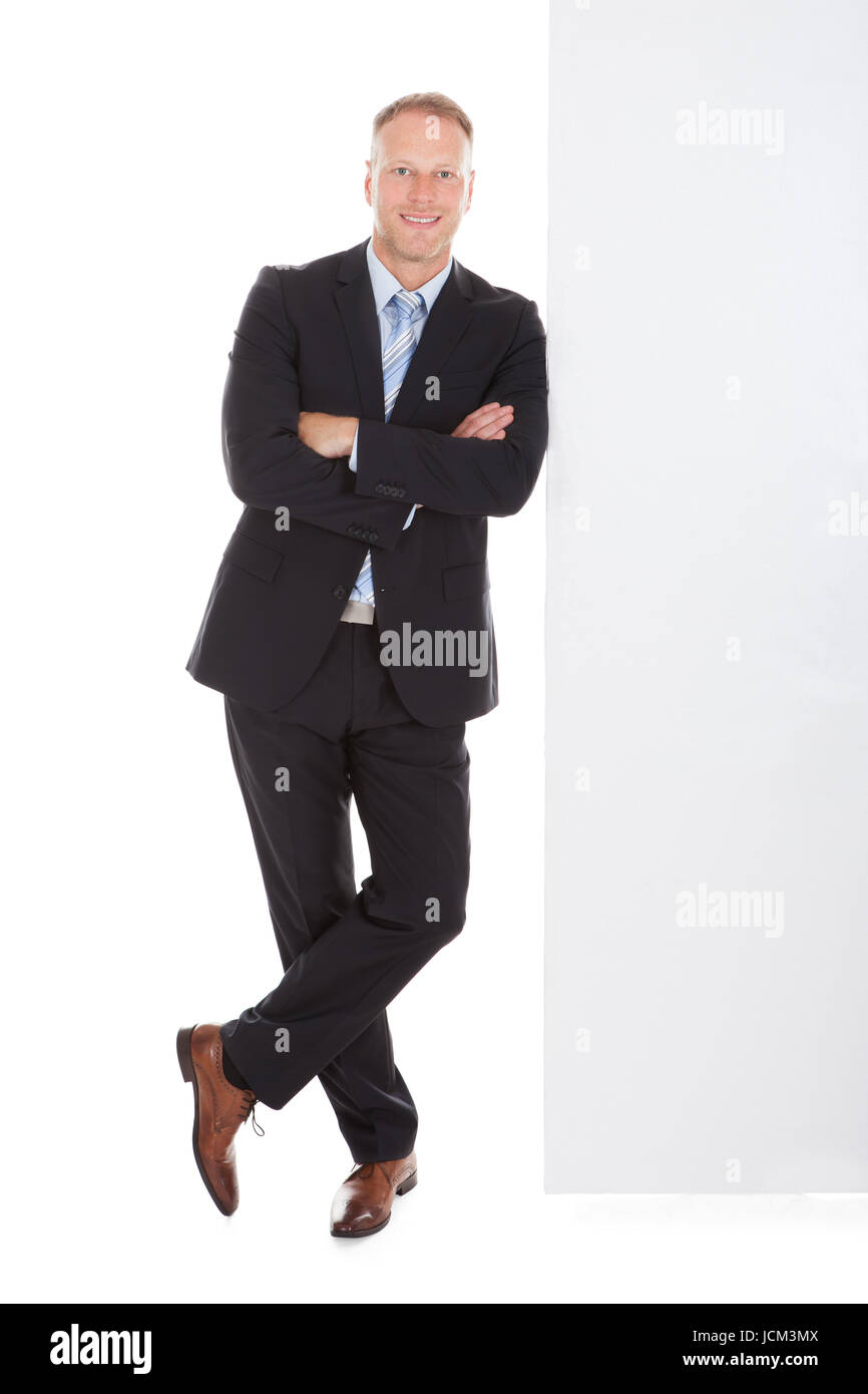 Full length portrait of mid adult businessman leaning over white ...