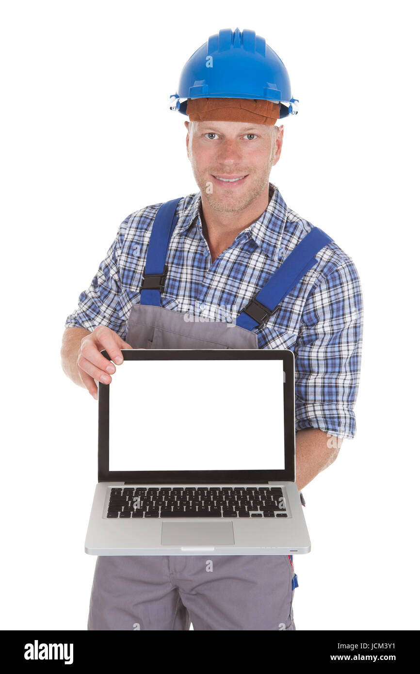 Portrait of young manual worker displaying laptop over white background ...
