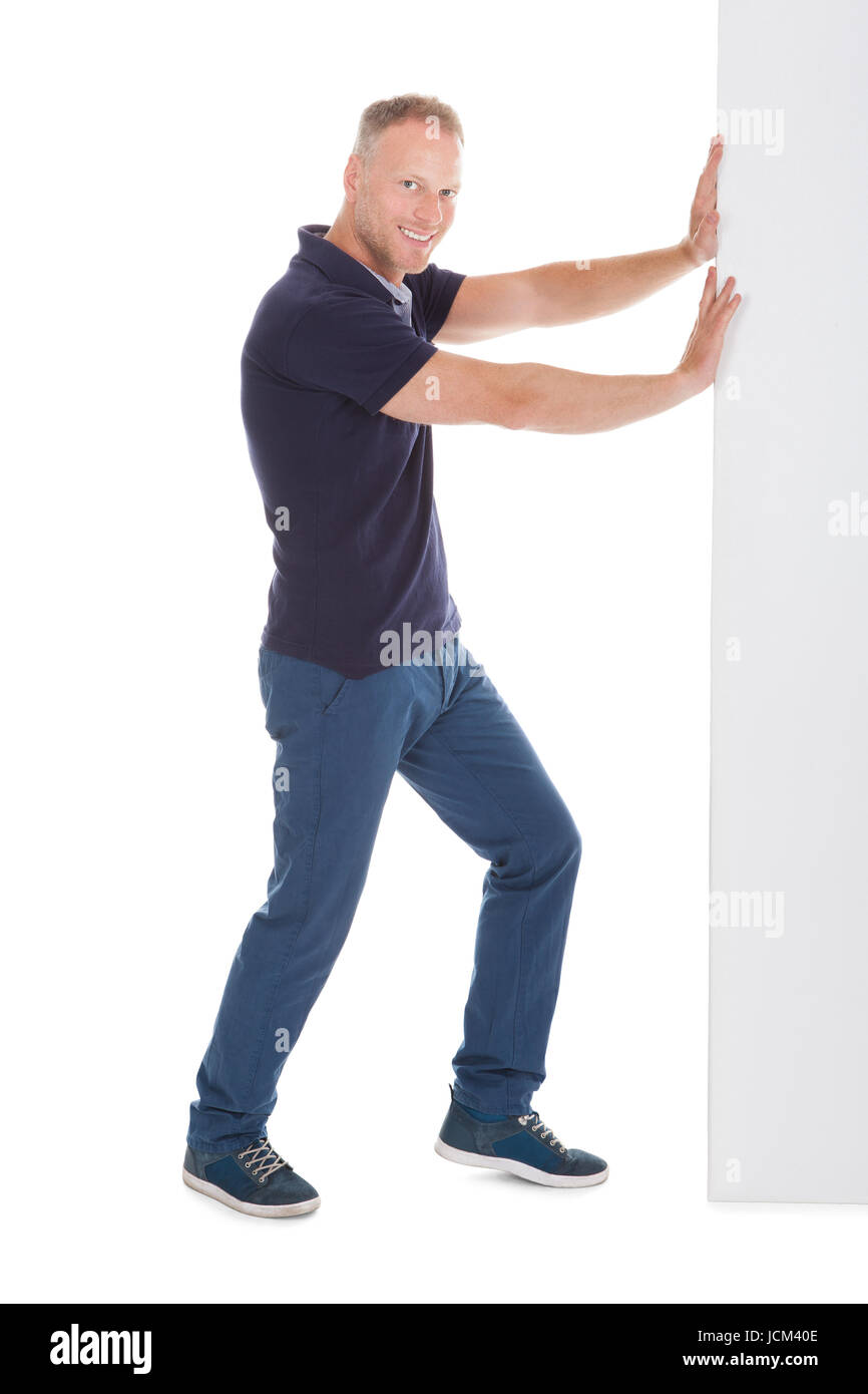 Full length portrait of confident man pushing billboard over white ...