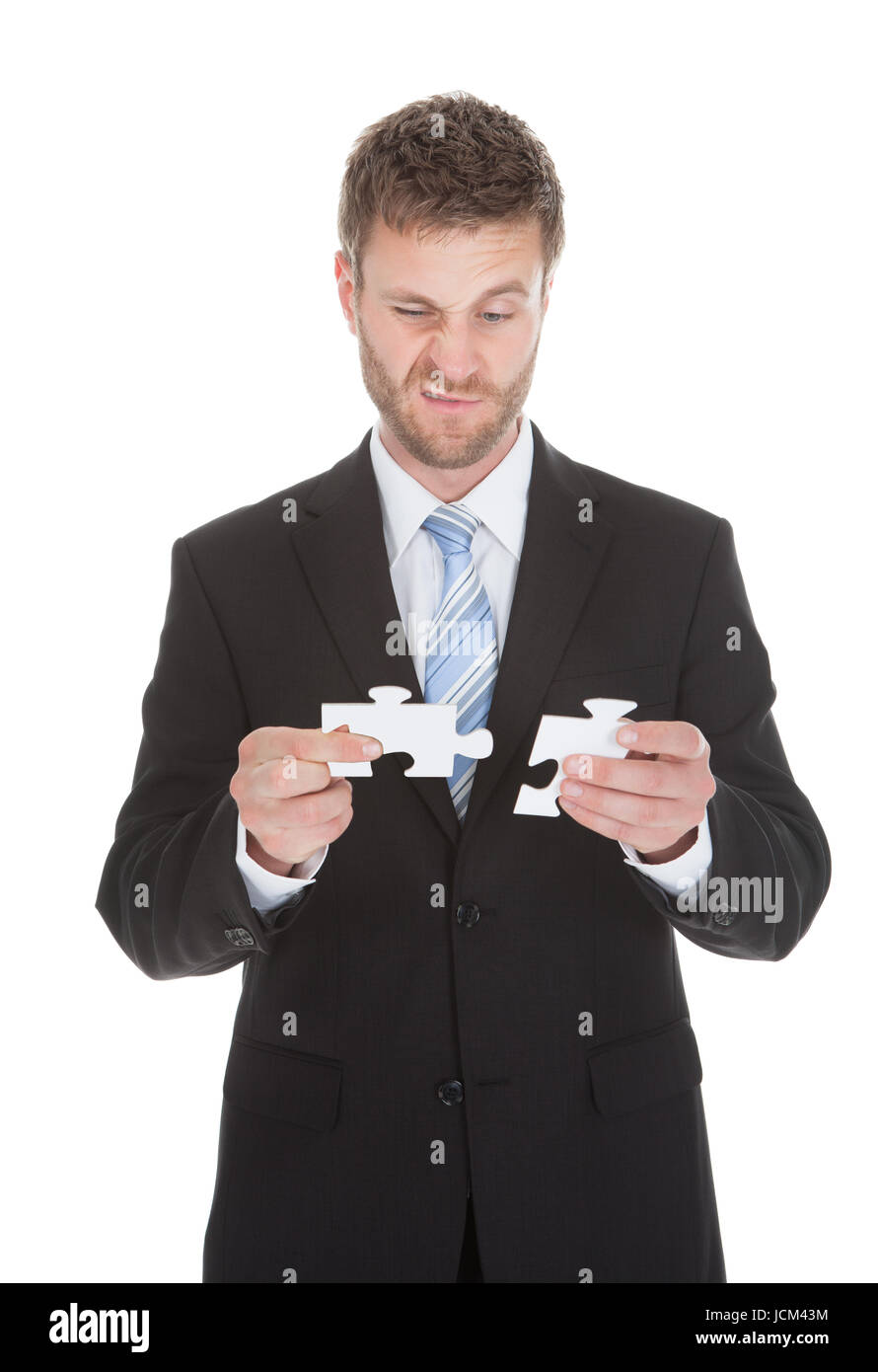 Confused businessman holding puzzle pieces over white background Stock ...