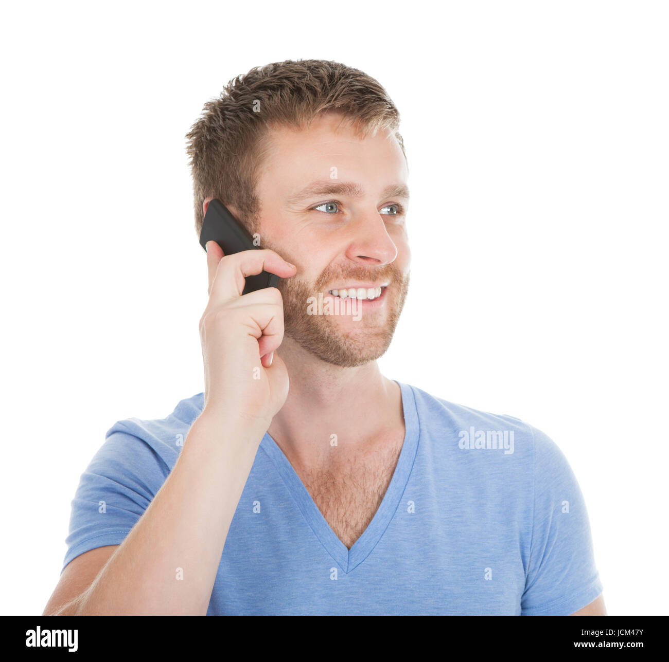 Happy mid adult man answering cell phone while looking away over white ...