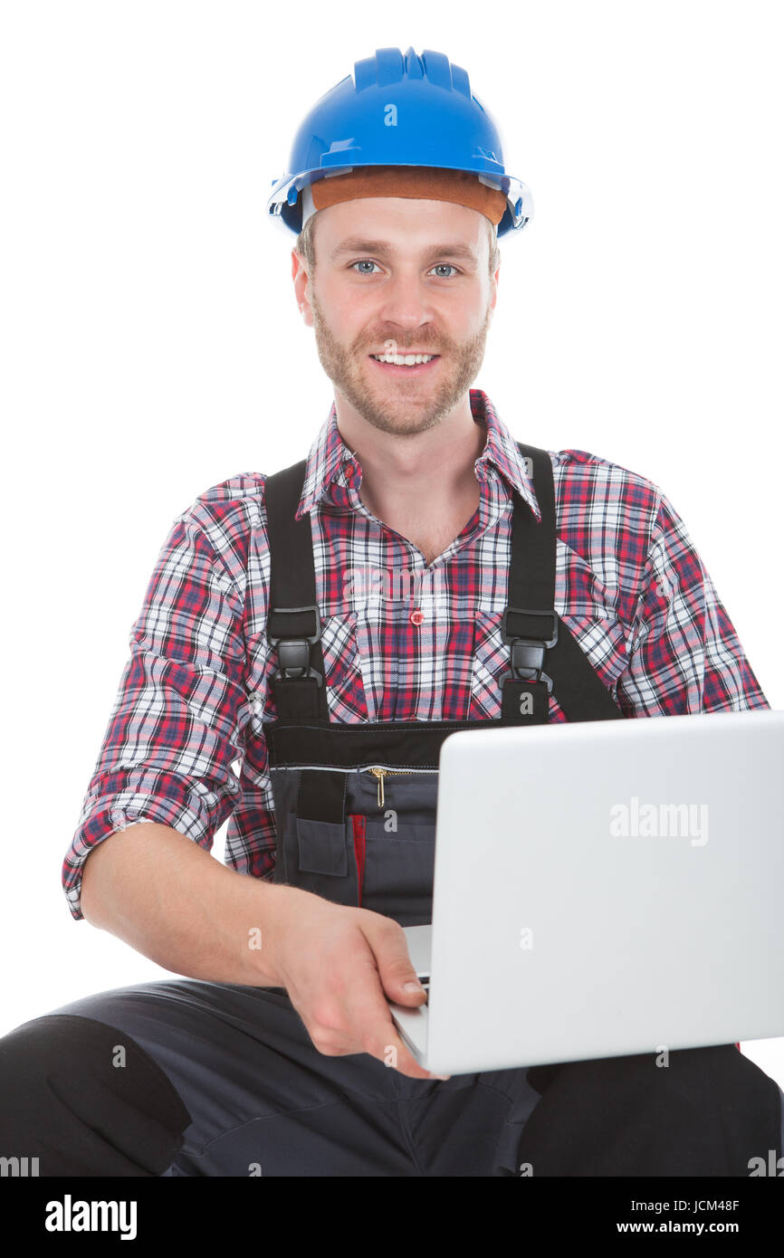 Full length portrait of confident manual worker using laptop while ...