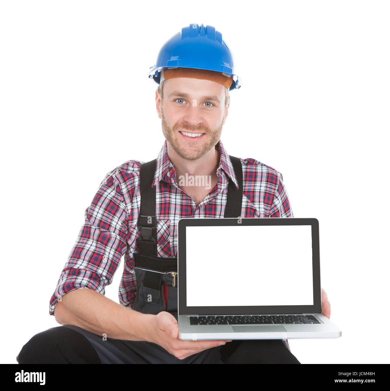 Portrait of young manual worker displaying laptop over white background ...