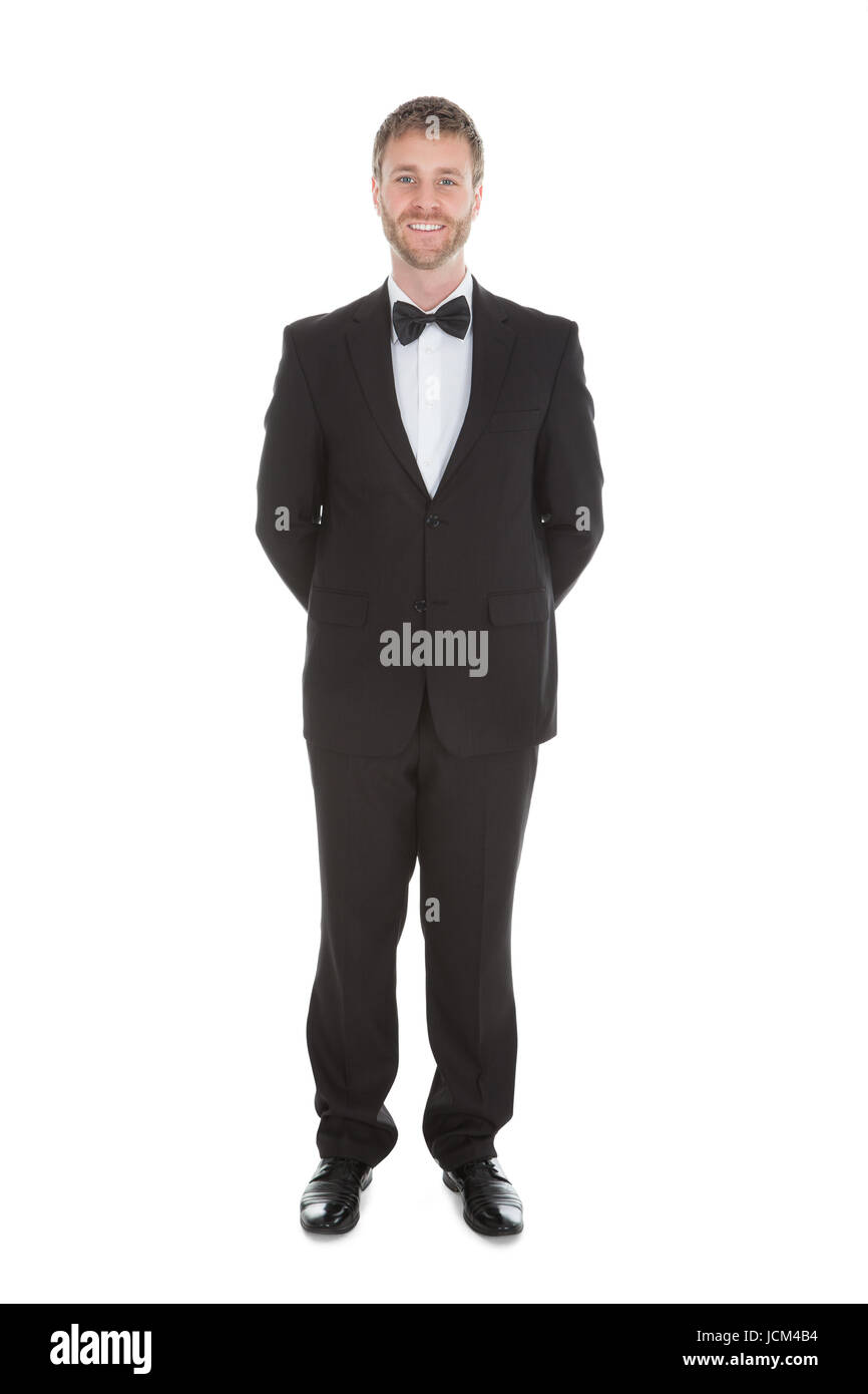 Full length portrait of confident waiter standing hands behind back ...