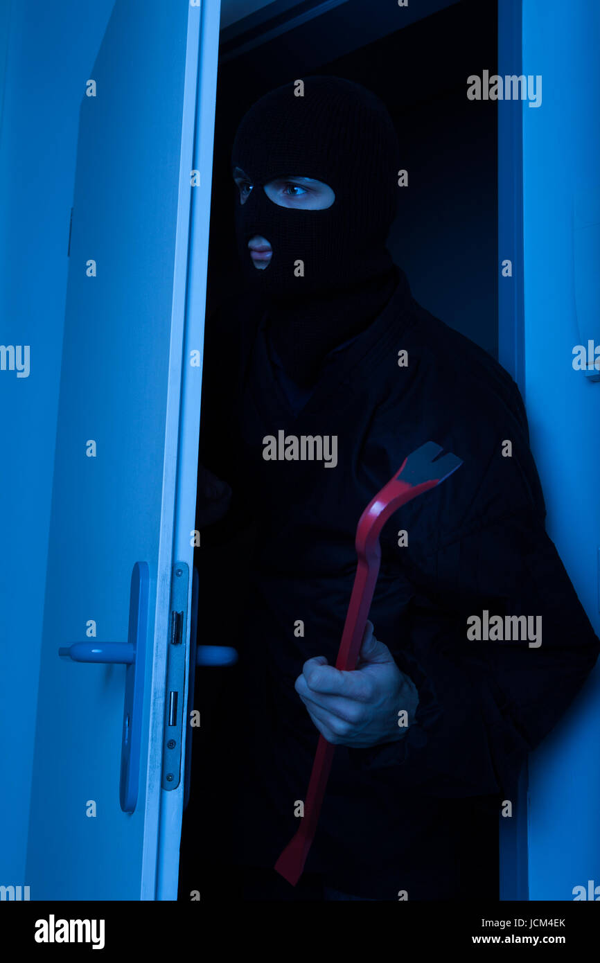 Thief holding crowbar while secretly entering into house Stock Photo ...