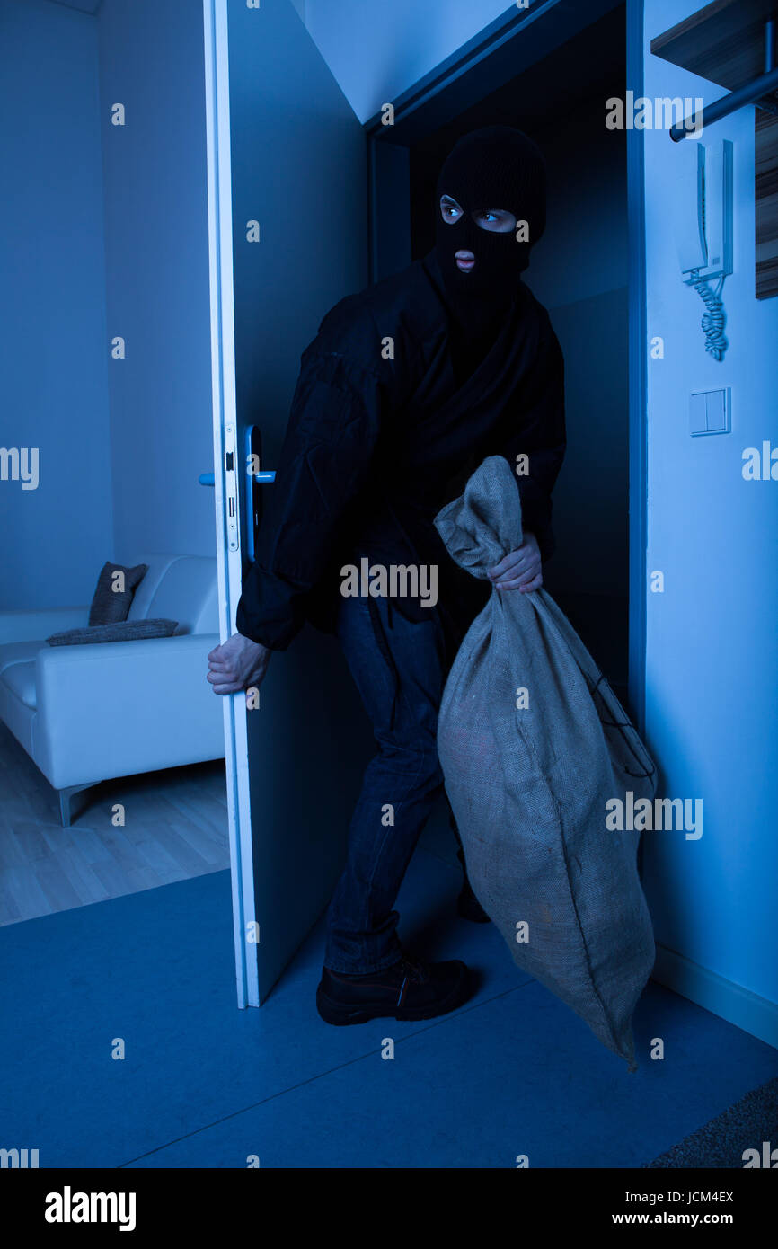 Full length of thief carrying sack while exiting house Stock Photo - Alamy
