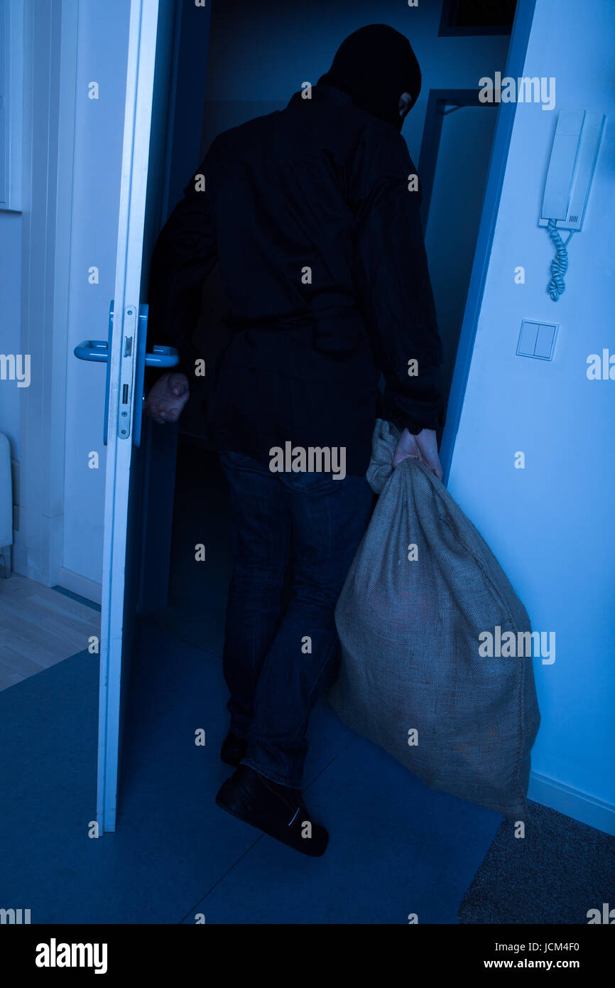 Full length of thief carrying sack while exiting house Stock Photo - Alamy