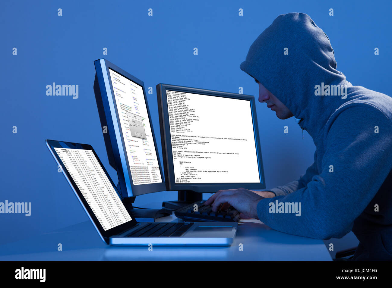 Side view of hacker using multiple computers to steal data at table Stock Photo - Alamy