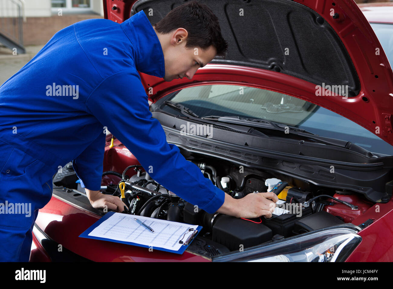 Side view of young mechanic in uniform repairing car Stock Photo - Alamy
