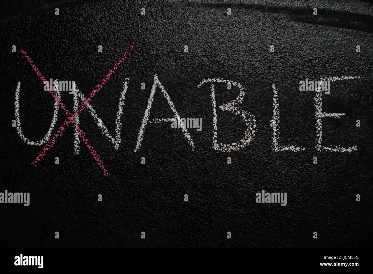 Cross over unable word drawn with chalk on blackboard. The unable is ...